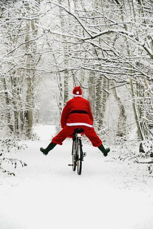 'Father Christmas Riding Bicycle in Snowy Woodland Path' Photographic ...