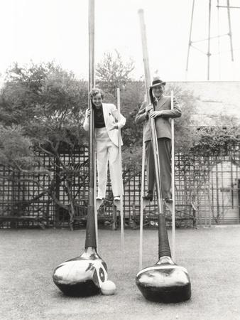 'Man and Woman on Stilts Holding Giant Golf Clubs' Photo | Art.com